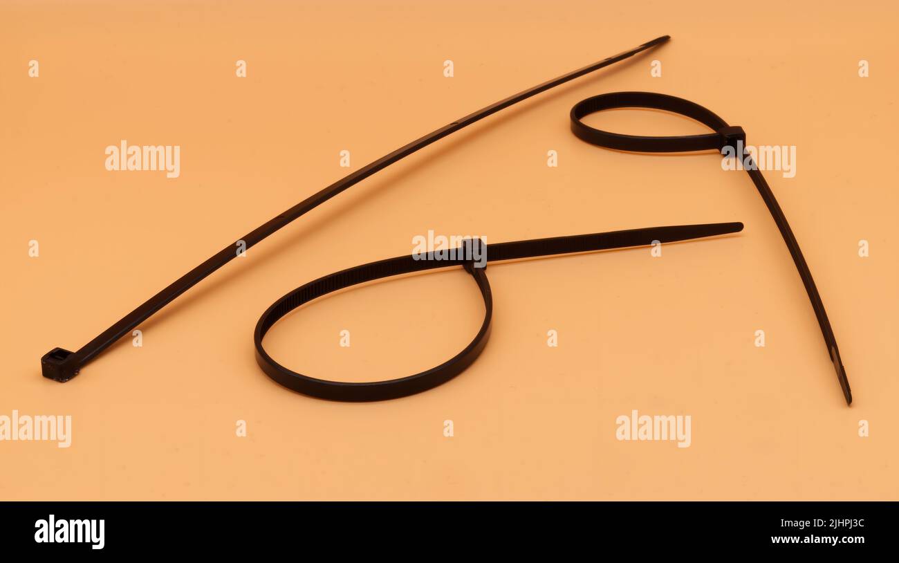 Black cable ties isolated on orange background. Plastic Tie Wraps Stock ...