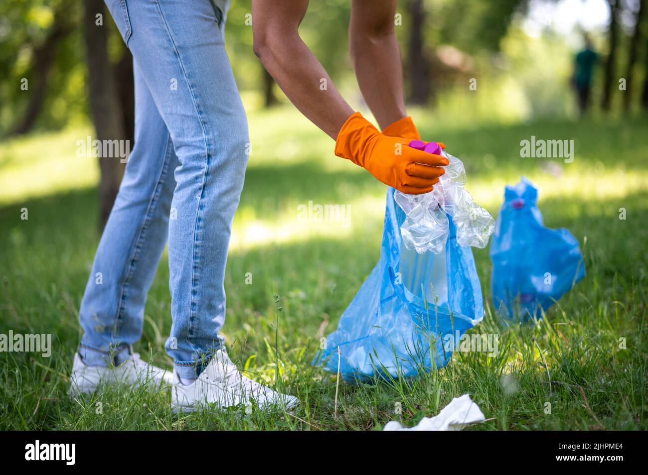 Lower half of man picking up trash in park Stock Photo - Alamy