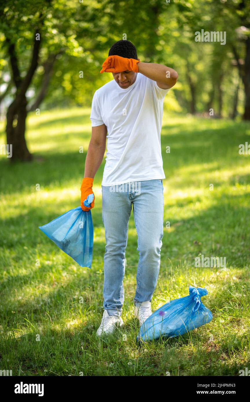 Man with garbage bags standing tired Stock Photo - Alamy