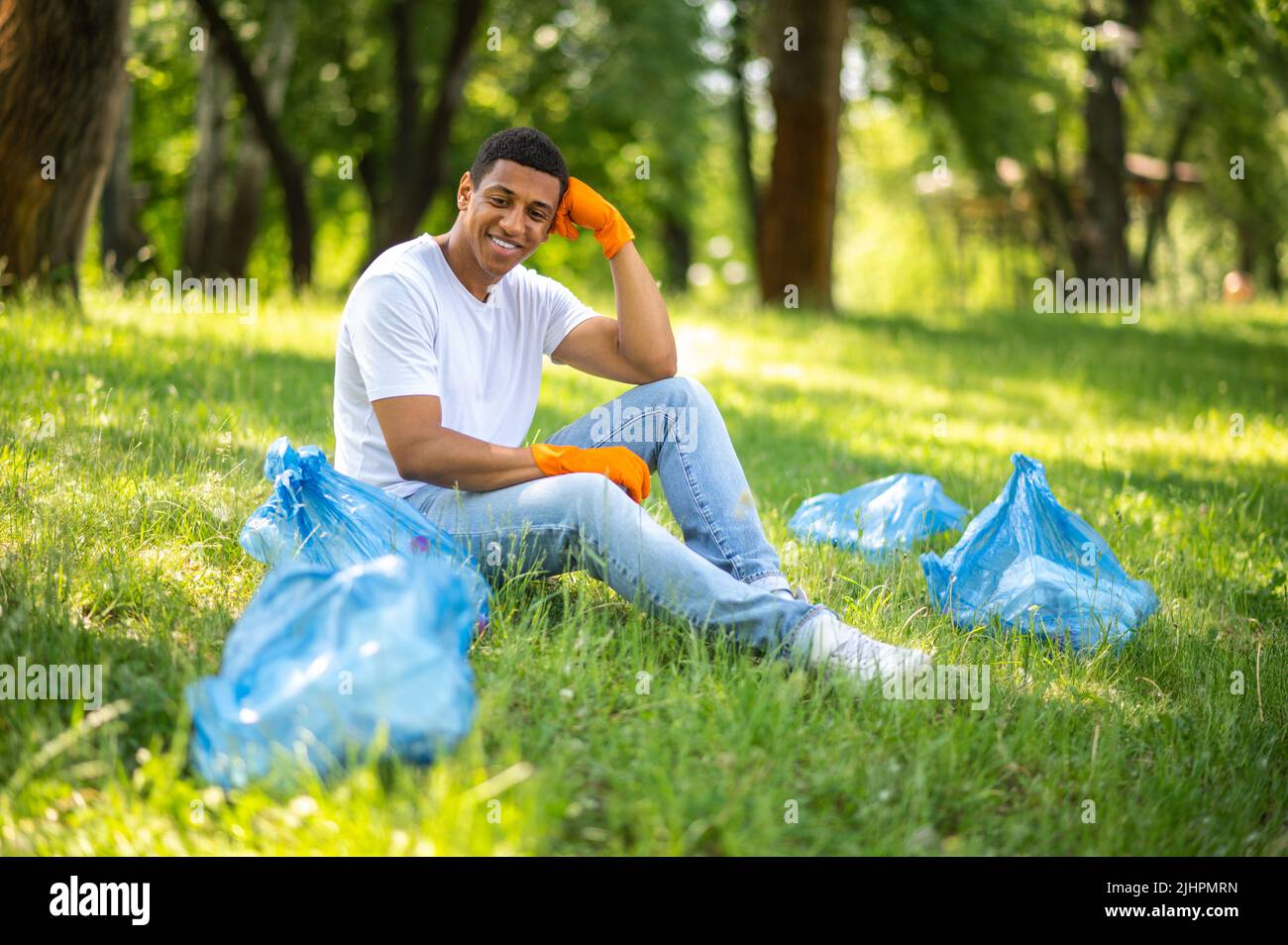 Guy smiling looking at collected garbage in park Stock Photo - Alamy