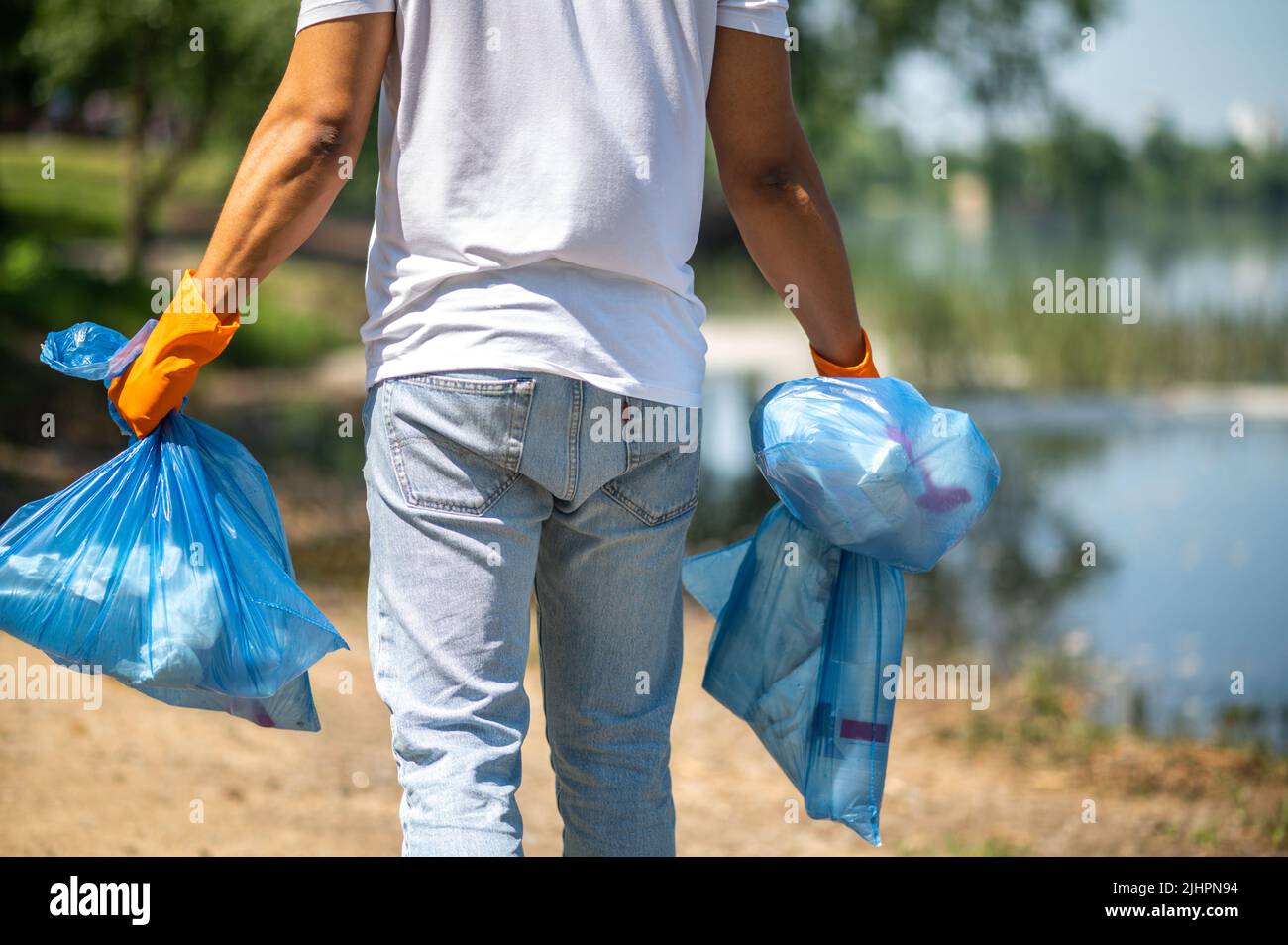 Back view of man holding trash bags Stock Photo - Alamy