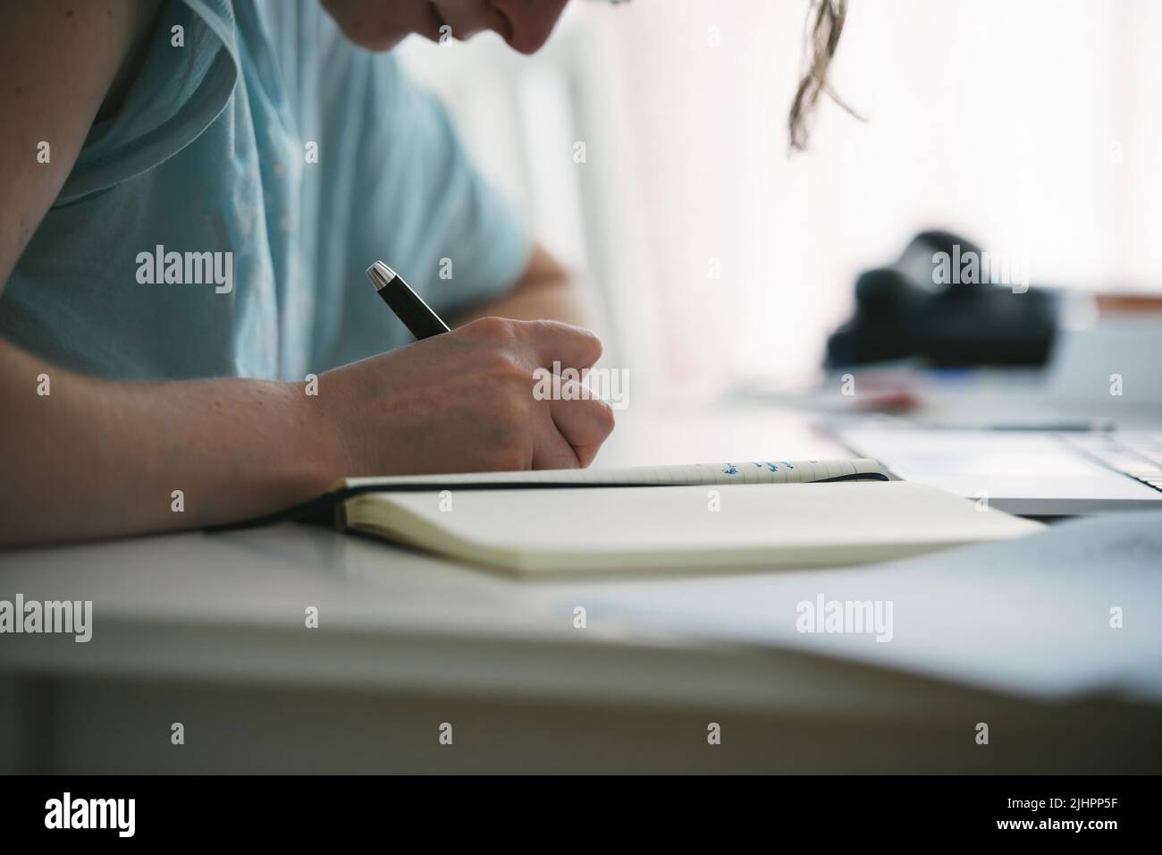 Side view of unrecognizable woman writing in hher notebook at the ...