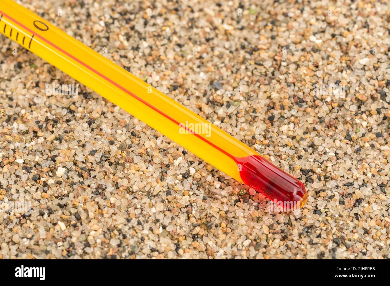 Glass red ink thermometer bulb on coarse sand background. For 2023 ...