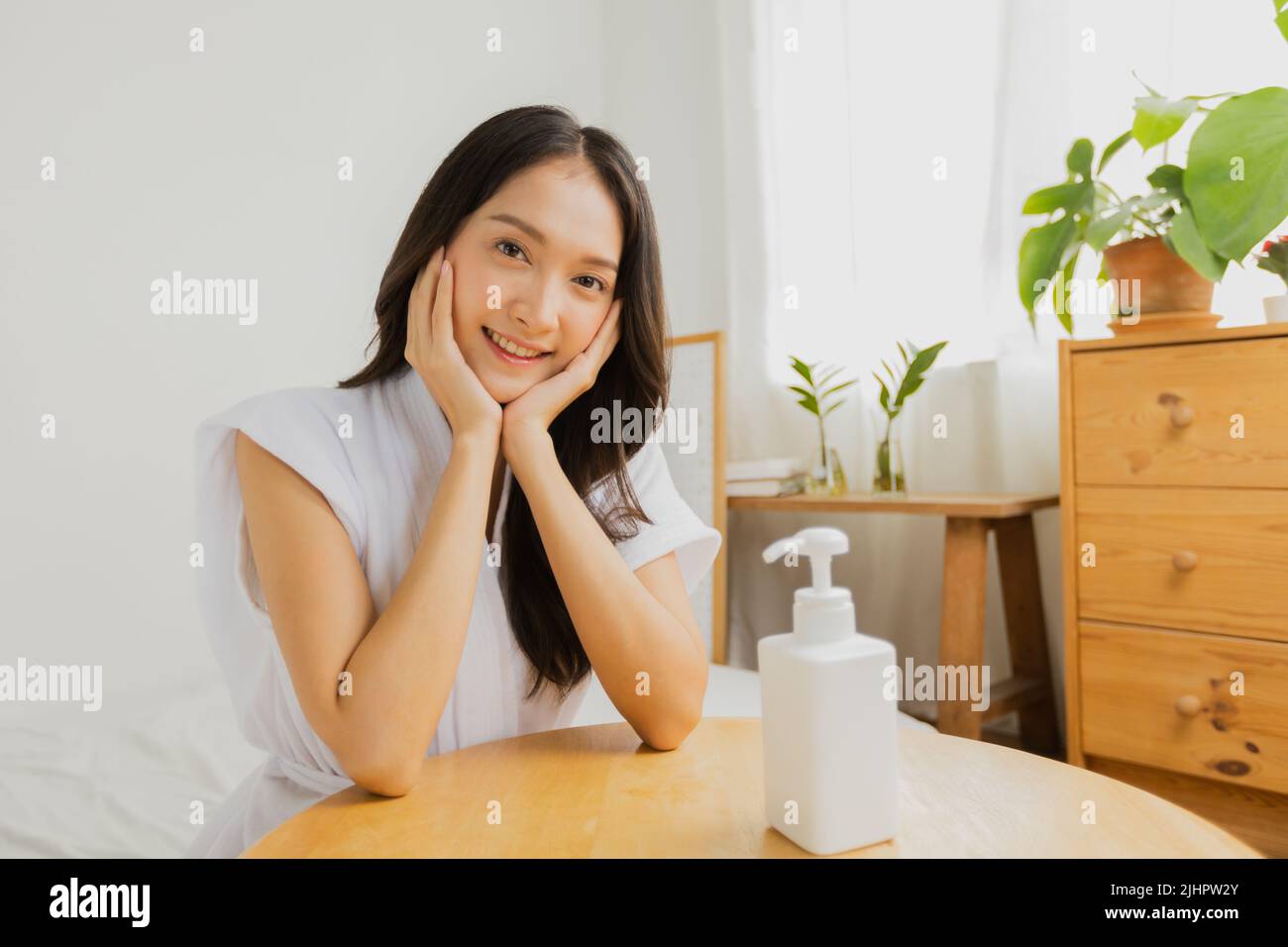 Portrait of beautiful Asian woman with skin lotion cream bottle on ...