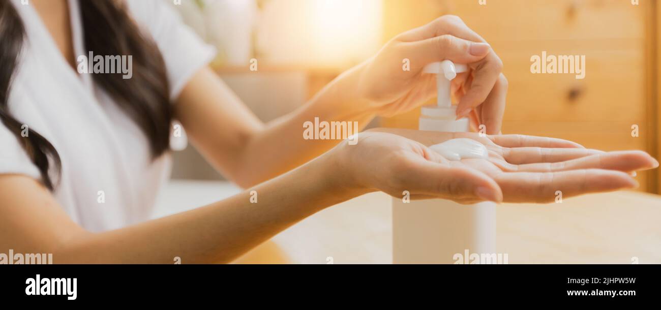 Close up hand of woman press bottle of skin lotion cream to apply ...