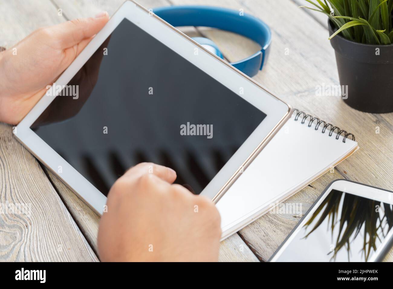 hands of a man holding tablet device over a wooden workspace table ...
