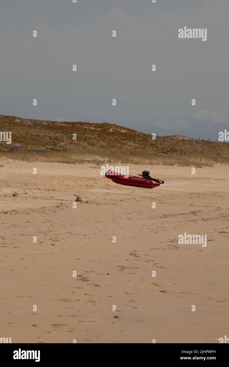 a red dinghy boat is on the beach, in front of the dune Stock Photo - Alamy