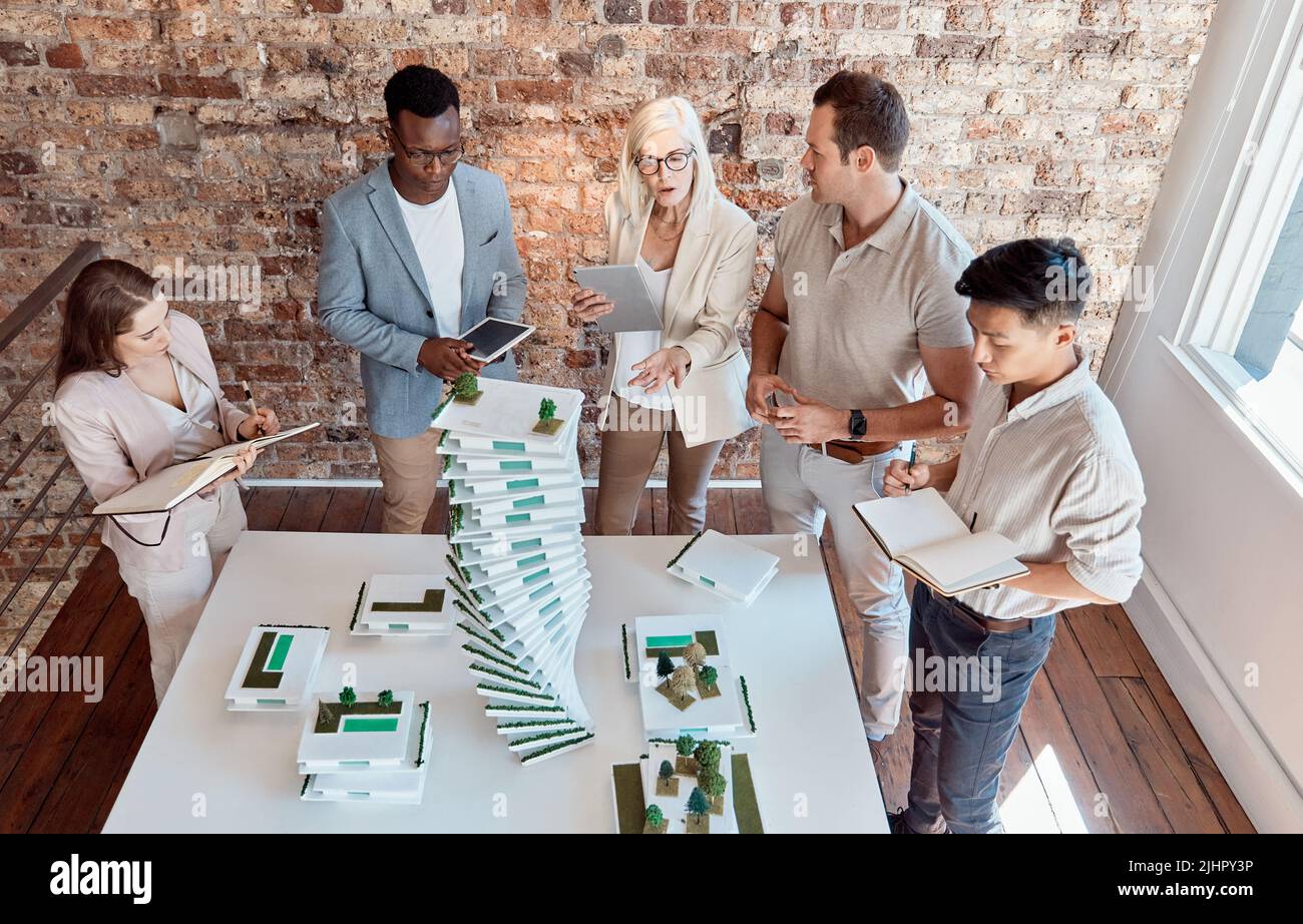 Group of diverse architects discussing plans, blueprints and schematics ...