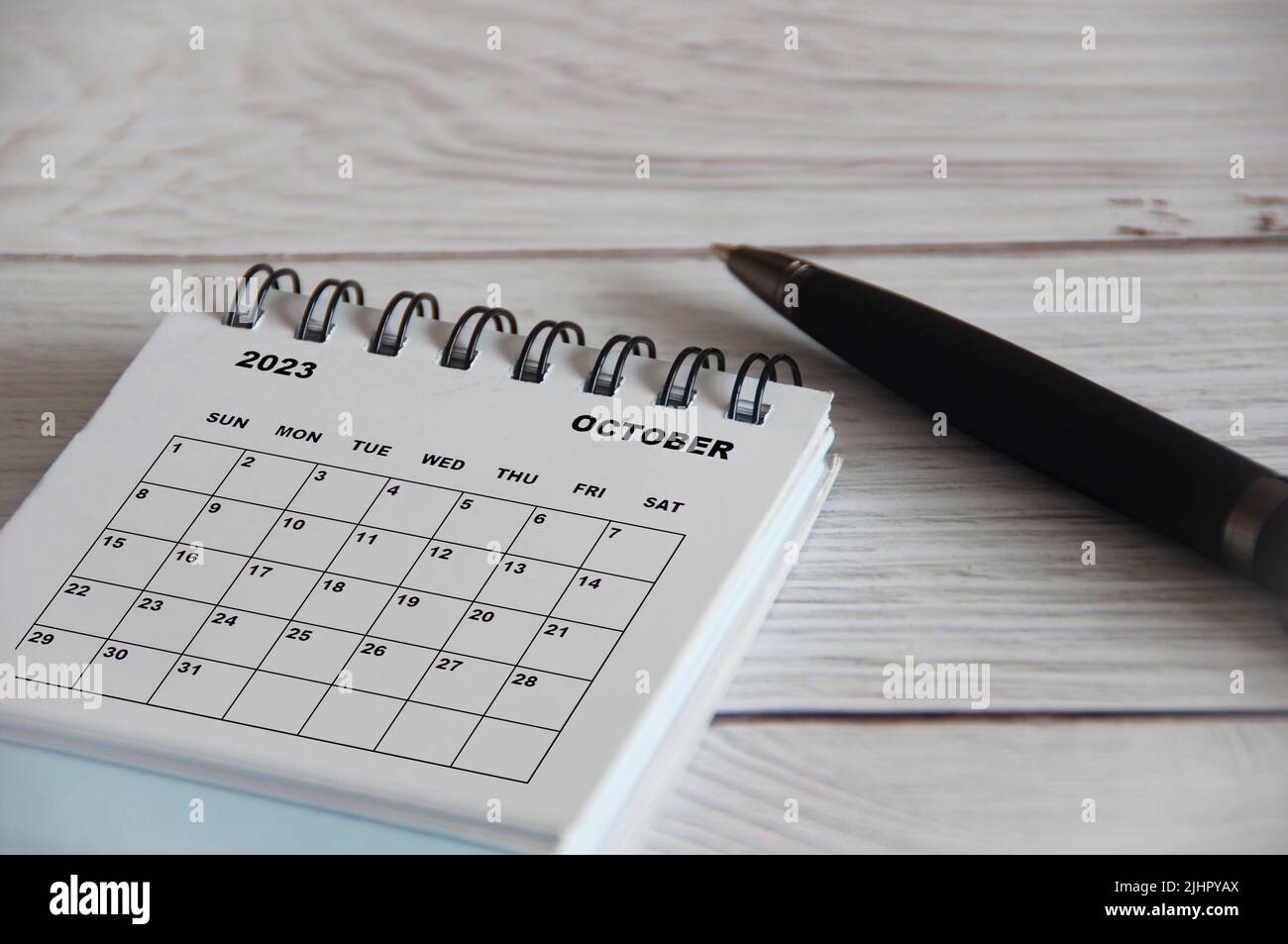 October 2023 white desk calendar with black pen on wooden table ...