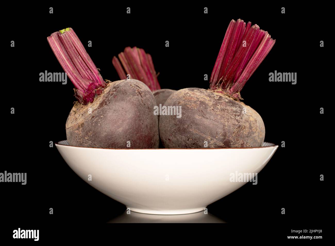 Three sweet red beets on a white ceramic plate, close-up, on a black ...