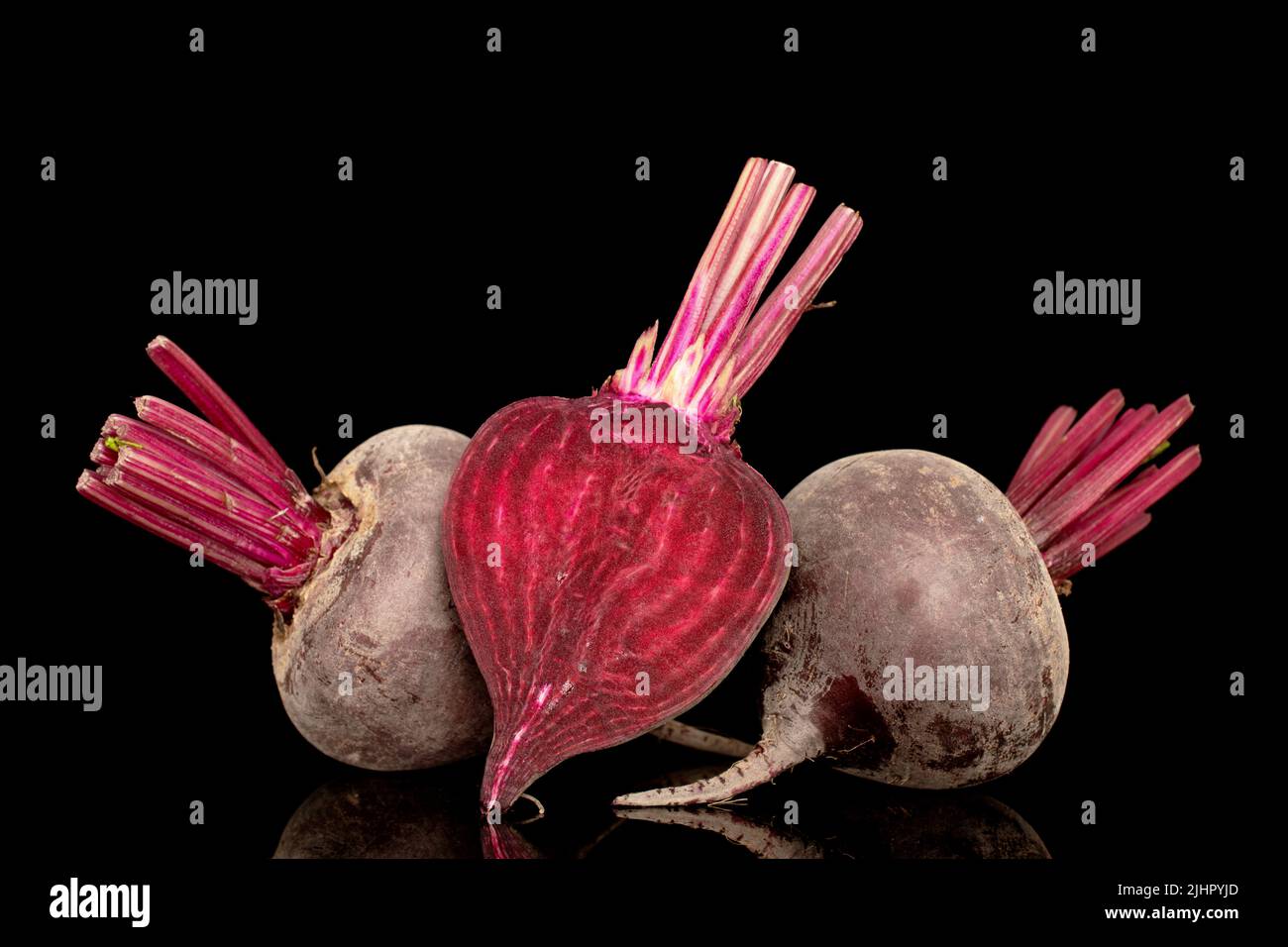 One half and two whole red beets, close-up, isolated on a black ...