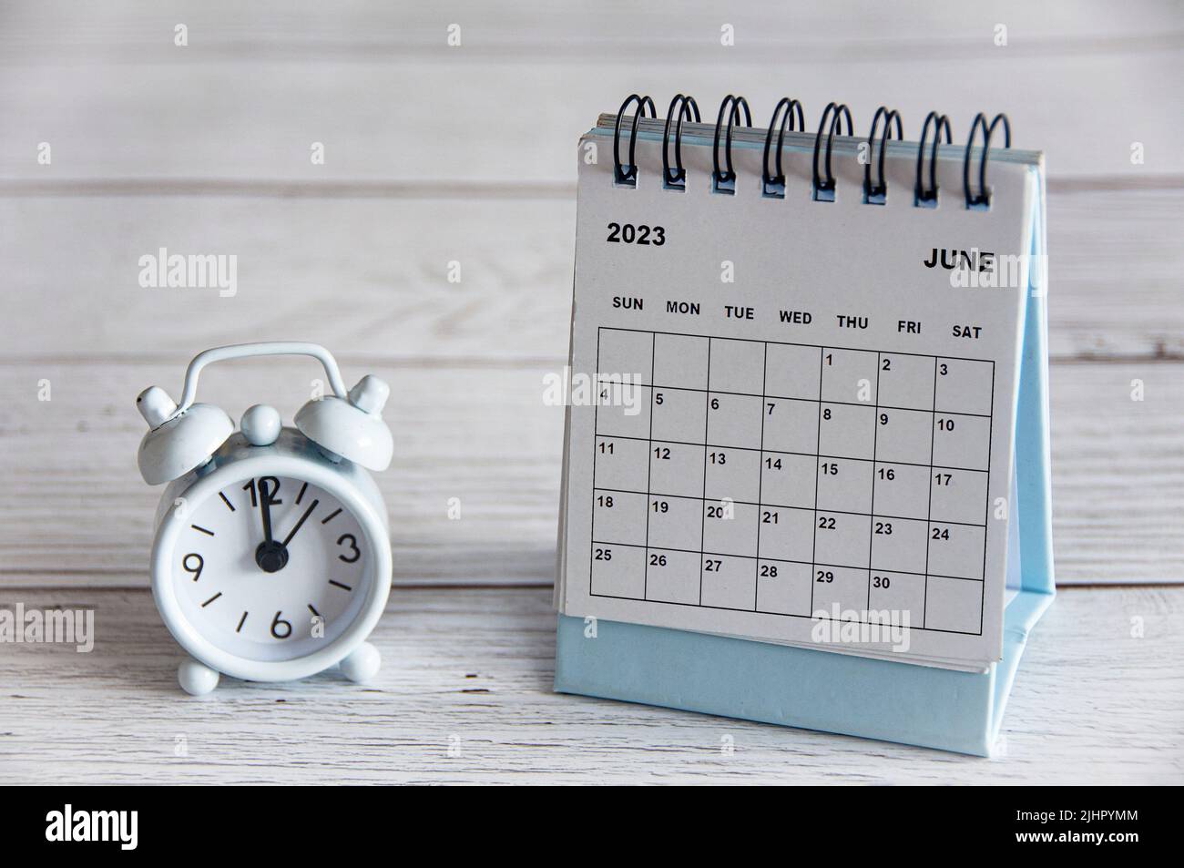 June 2023 white desk calendar on wooden table with alarm clock pointing ...