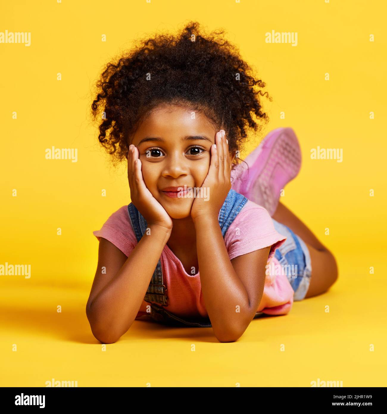 Studio portrait mixed race girl looking lying alone isolated against a ...