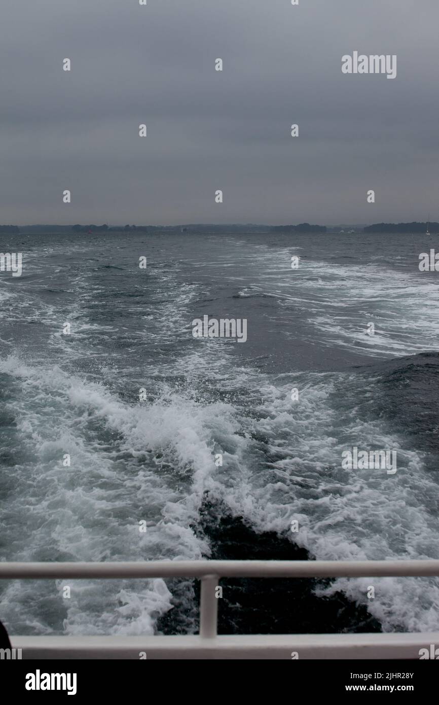 the boat's engine leaves a white trail on the ocean. The weather is ...