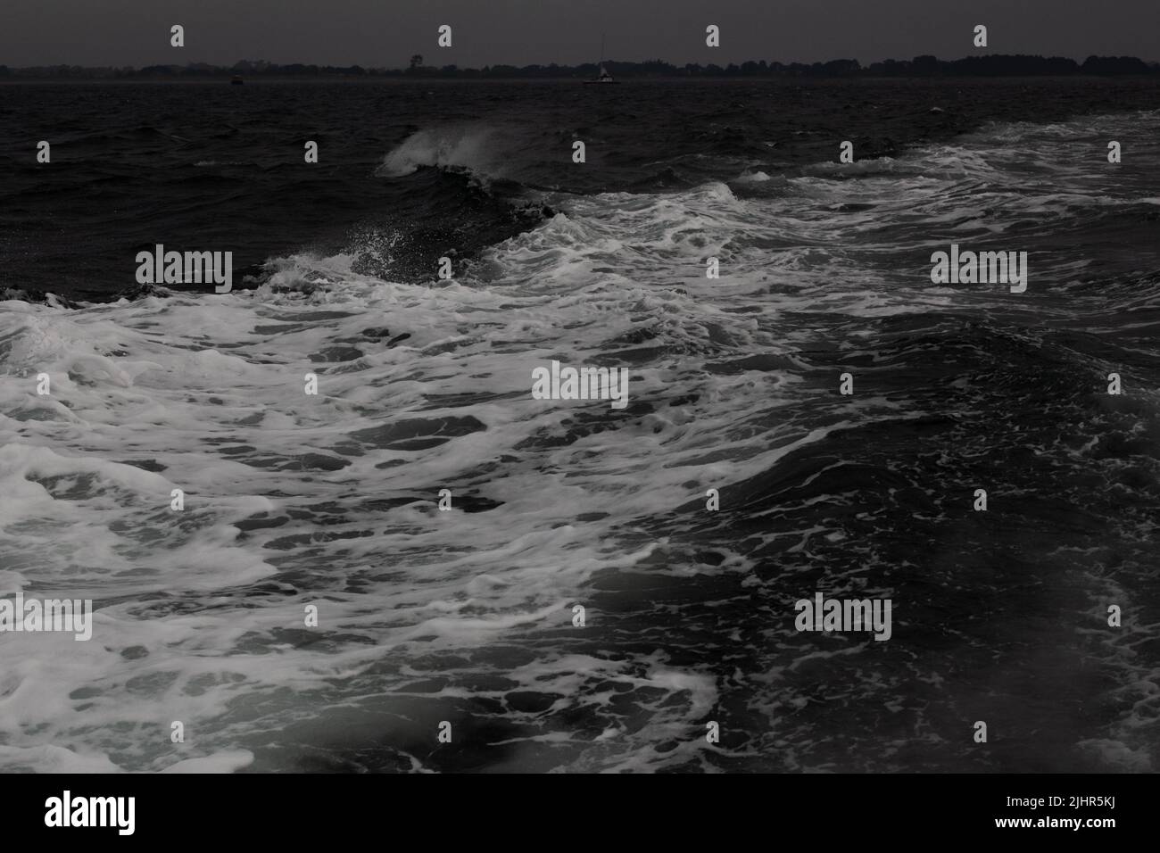 the boat's engine leaves a white trail on the ocean. The weather is ...