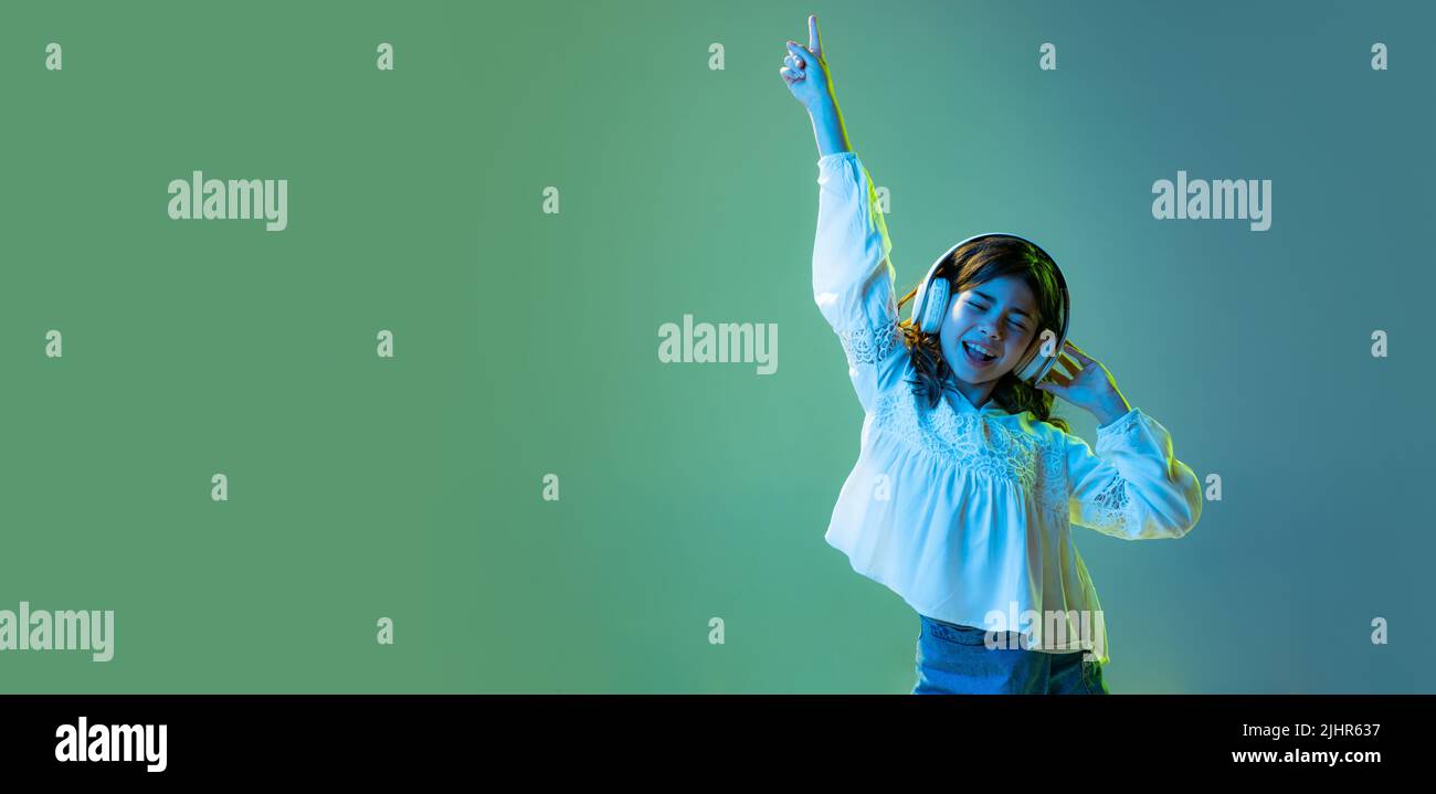 Dancing little girl, kid in casual style clothes isolated over cyan ...
