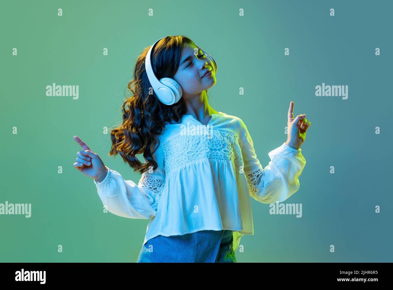 Dancing little girl, kid in casual style clothes isolated over cyan ...