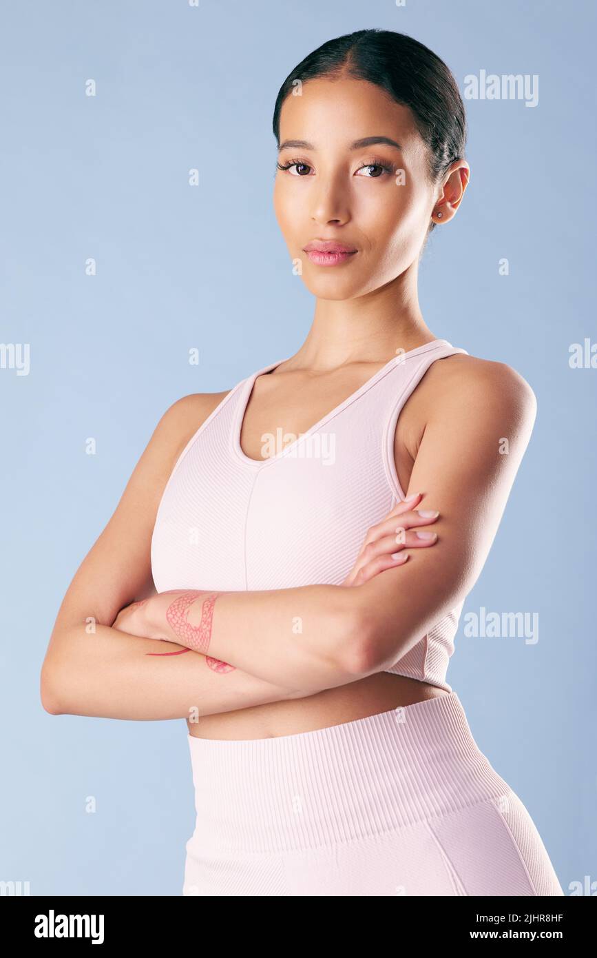 Mixed race fitness woman standing with her arms crossed in studio ...