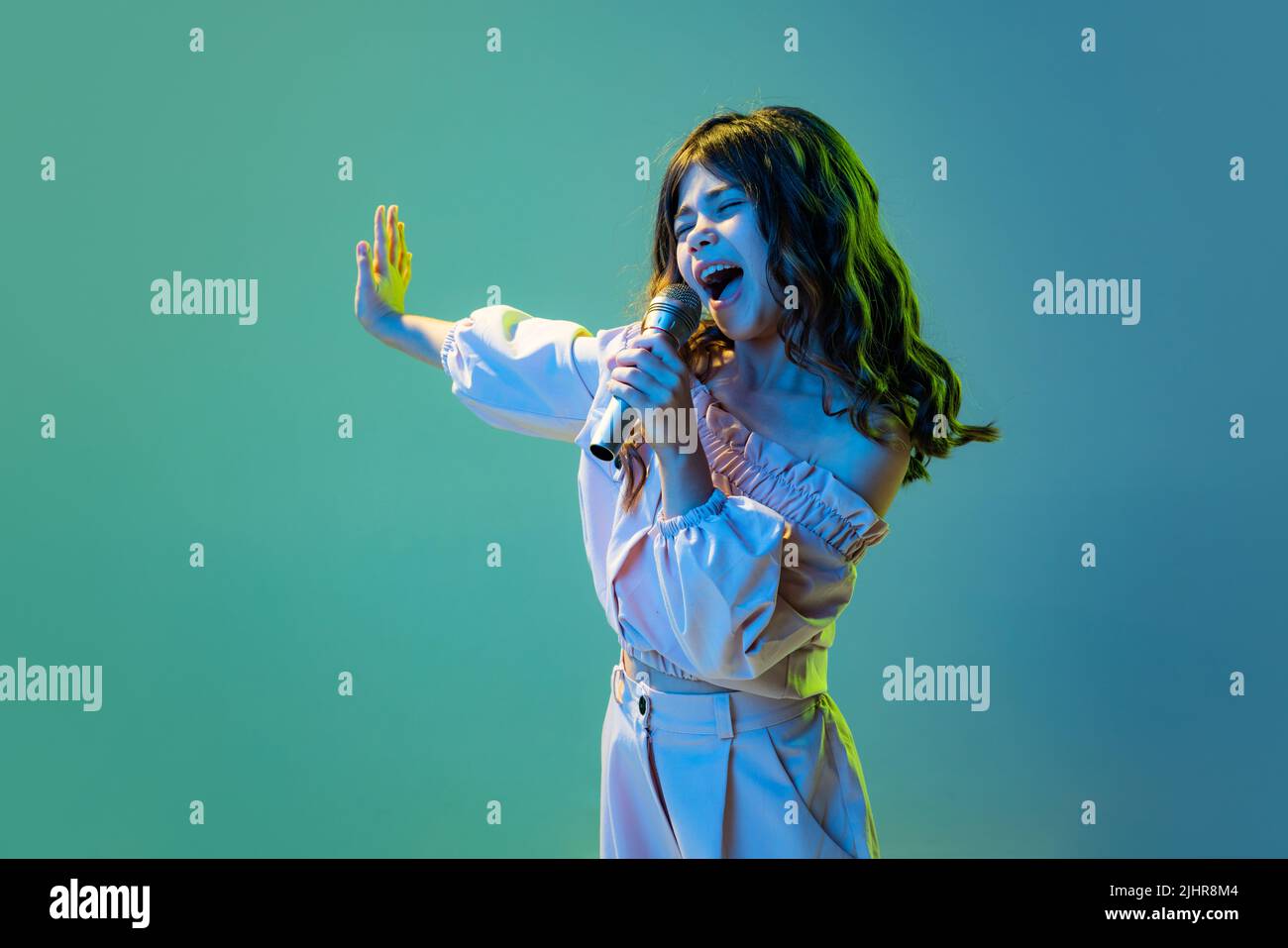Portrait of little girl, kid singing isolated over cyan color ...