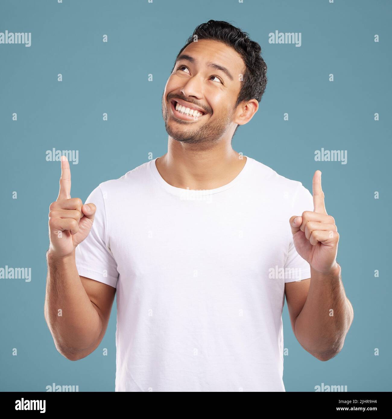 Handsome young mixed race man pointing towards copyspace while standing ...