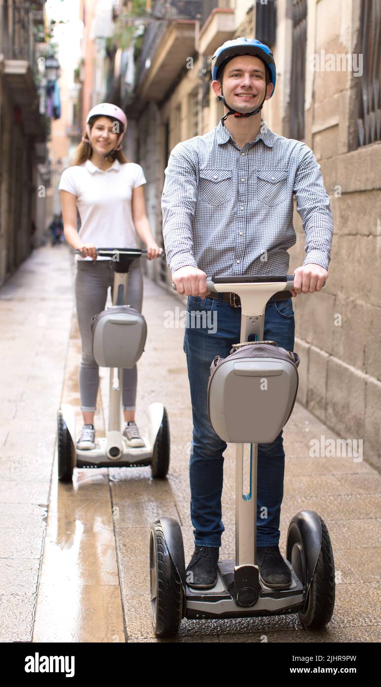 young couple guy and girl walking on segway in streets of european city ...