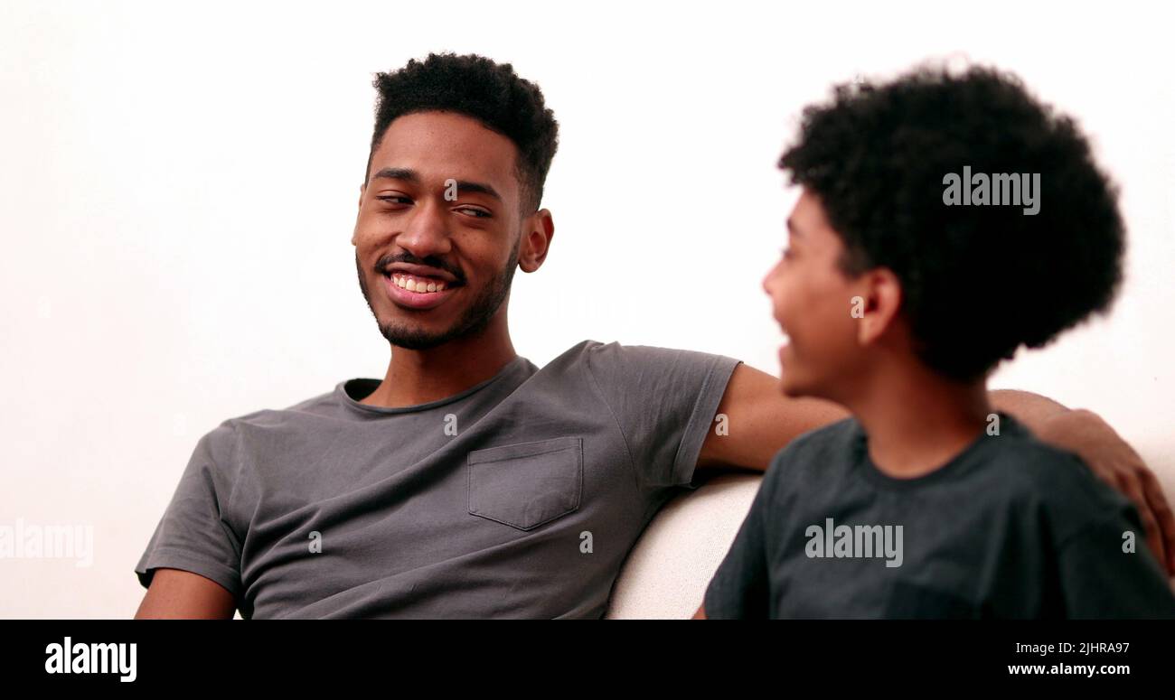 Older brother chatting with younger sibling. Candid mixed race two ...