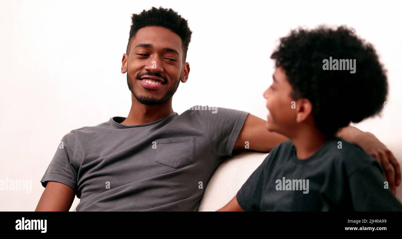 Older brother chatting with younger sibling. Candid mixed race two ...