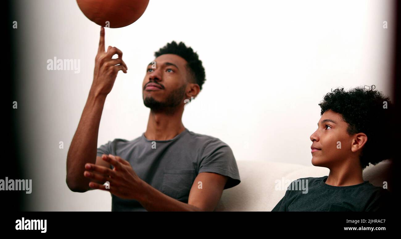 Older brother teaching younger sibling to spin basketball with finger ...