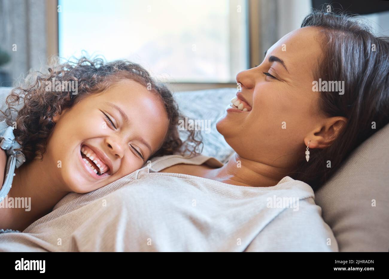 Joyful mother and little daughter lying her head on her mothers chest ...