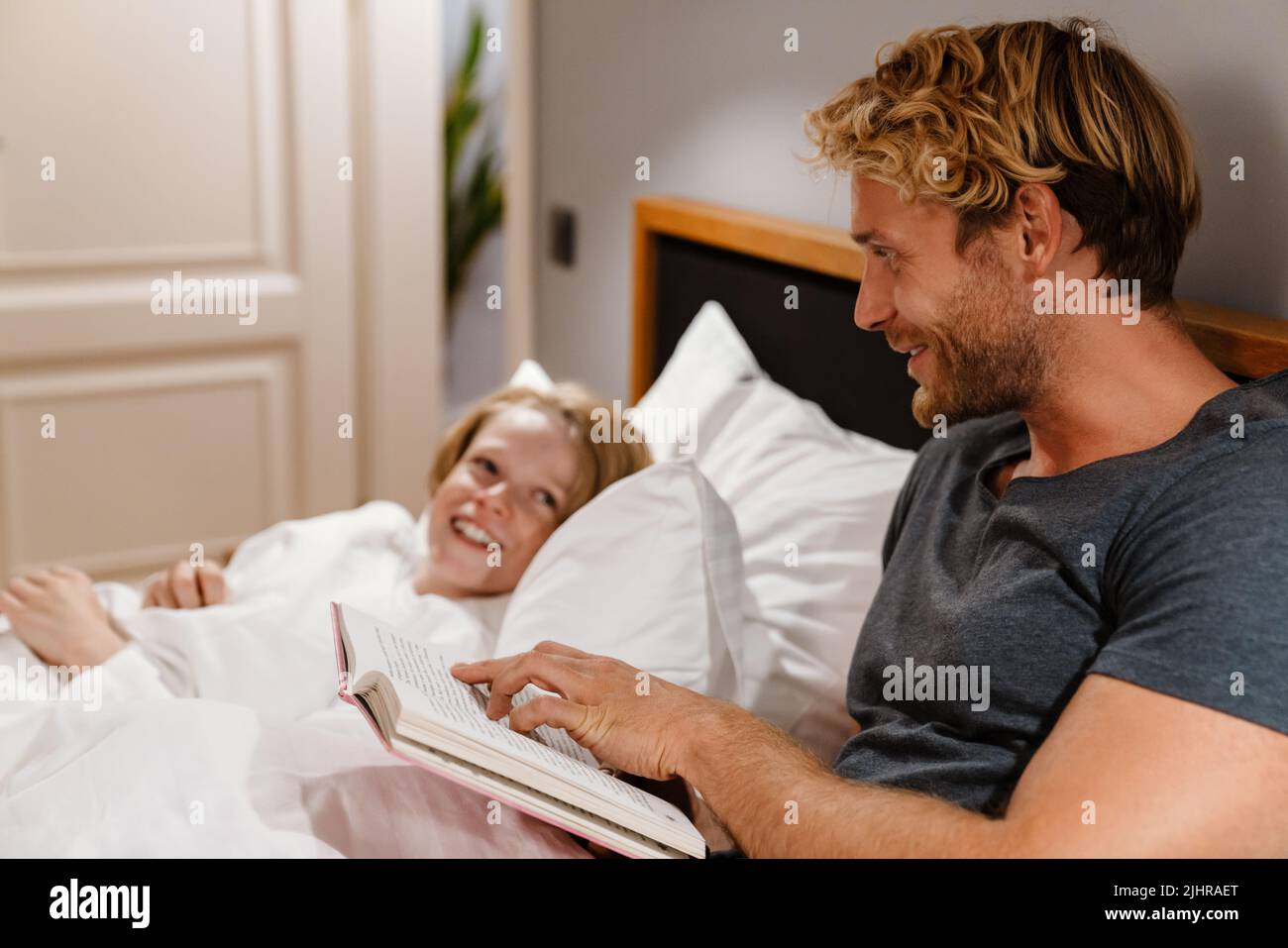 White man reading book to his son while lying in bed at home Stock ...