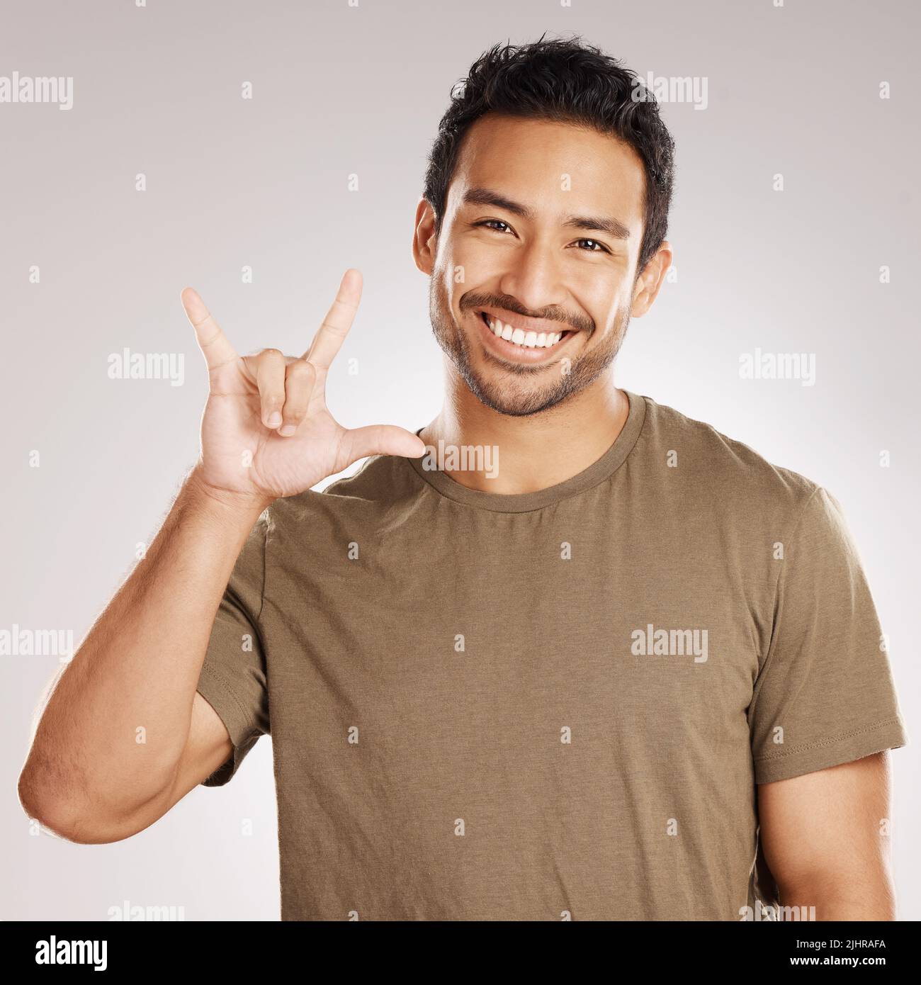 Handsome young mixed race man gesturing rock on while standing in ...