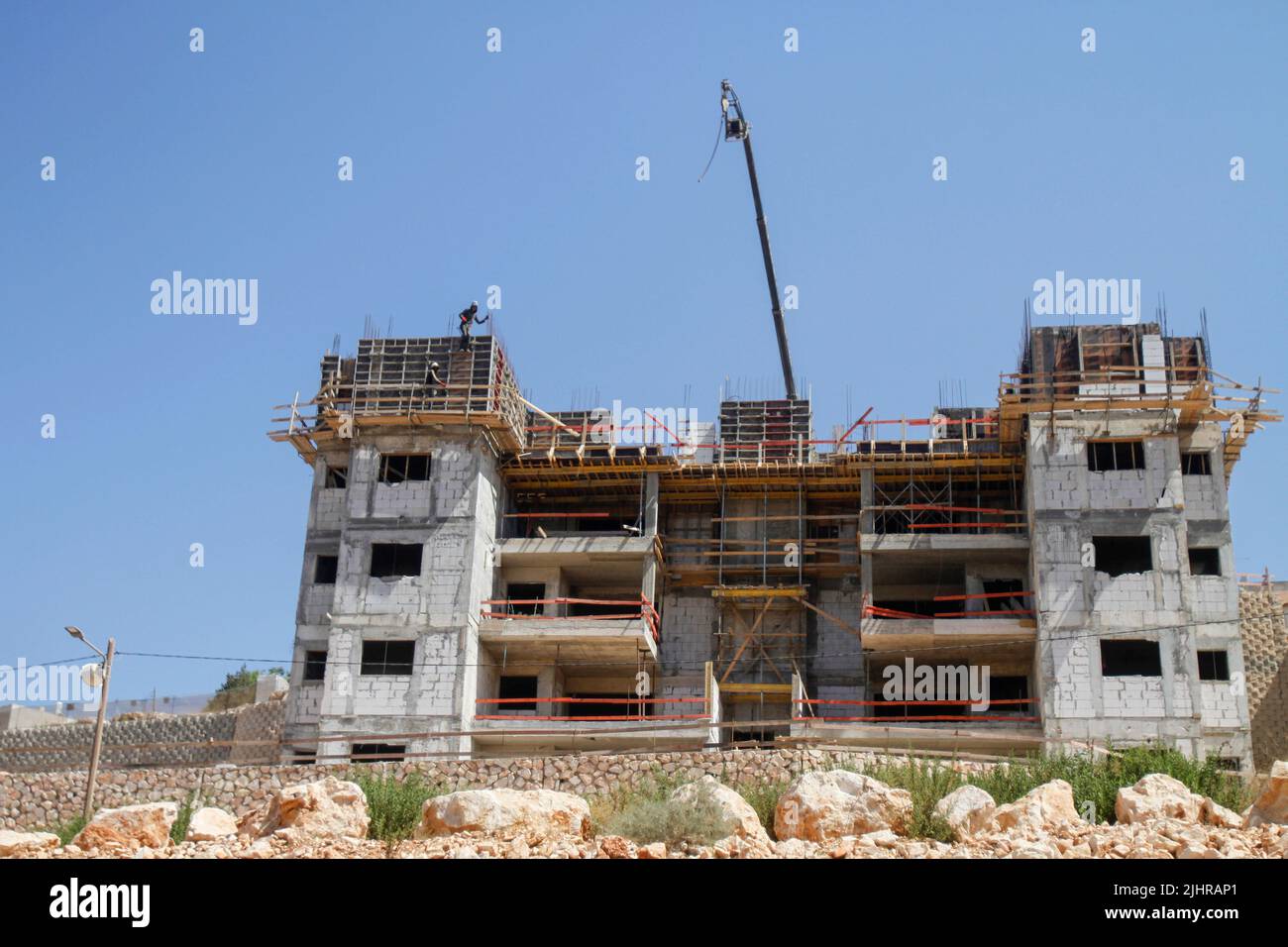 Workers work on the construction of new buildings in the Israeli ...
