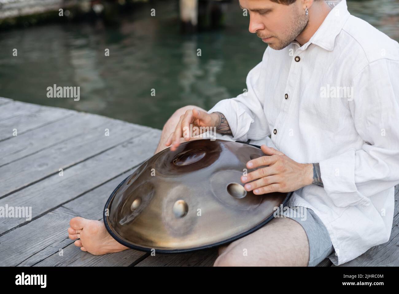 Barefoot musician playing metal hang drum on pier in Venice Stock Photo ...