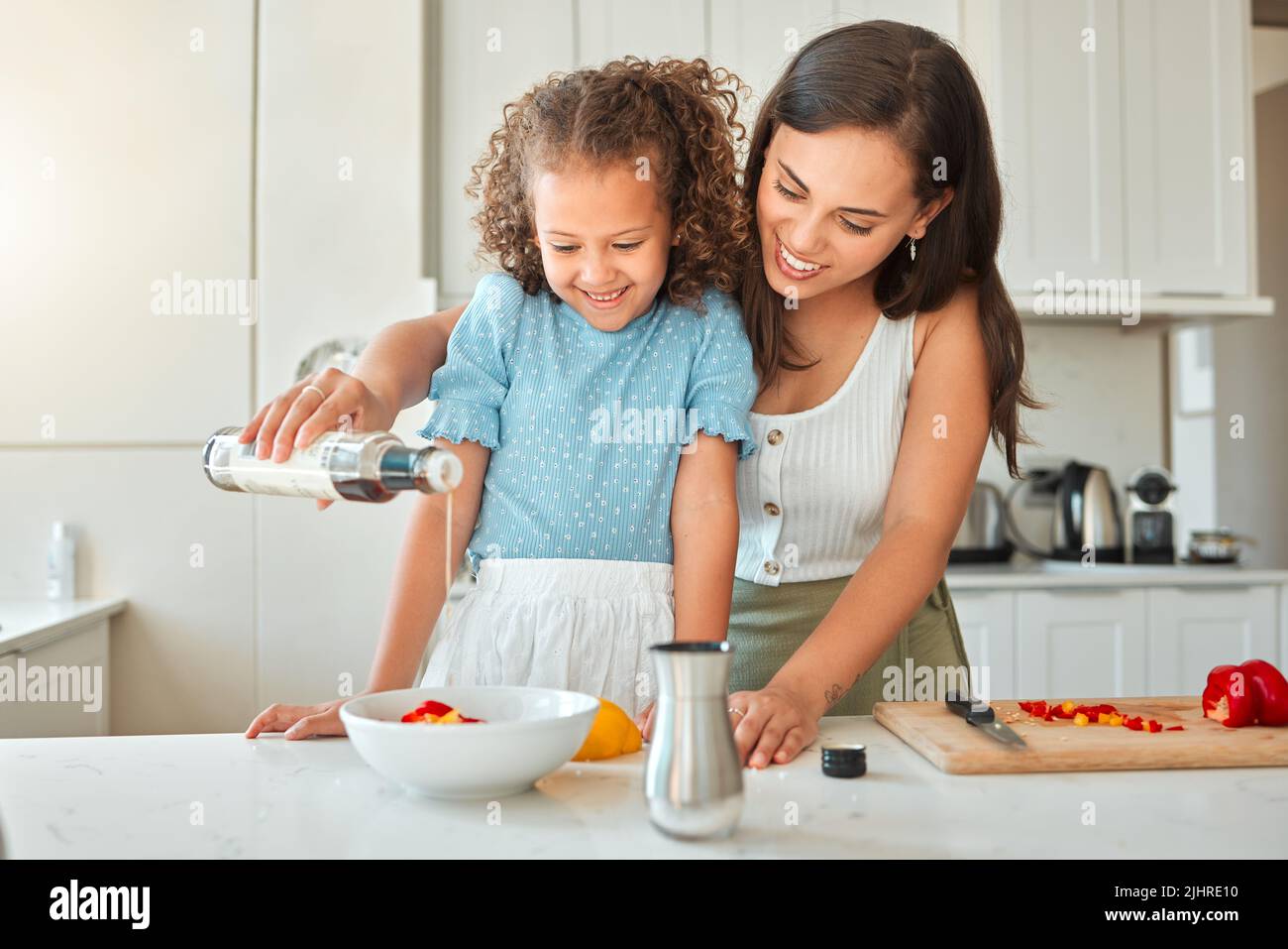 Happy mixed race mother and little daughter cooking together in the ...