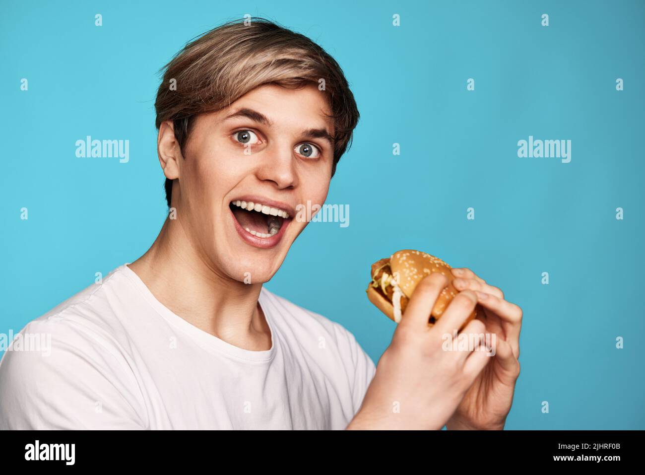 Very hungry young man holding tasty hamburger Stock Photo - Alamy