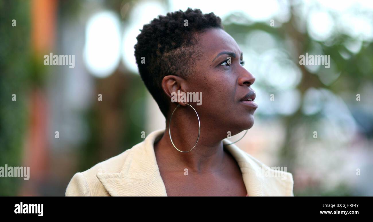 Pensive African woman walking outside. 40s Thoughtful black person ...