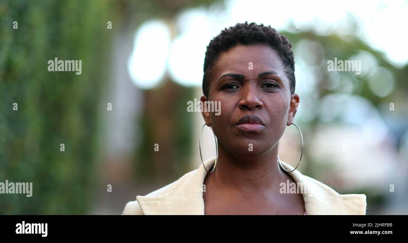 Serious African woman walking outside in sidewalk Stock Photo - Alamy