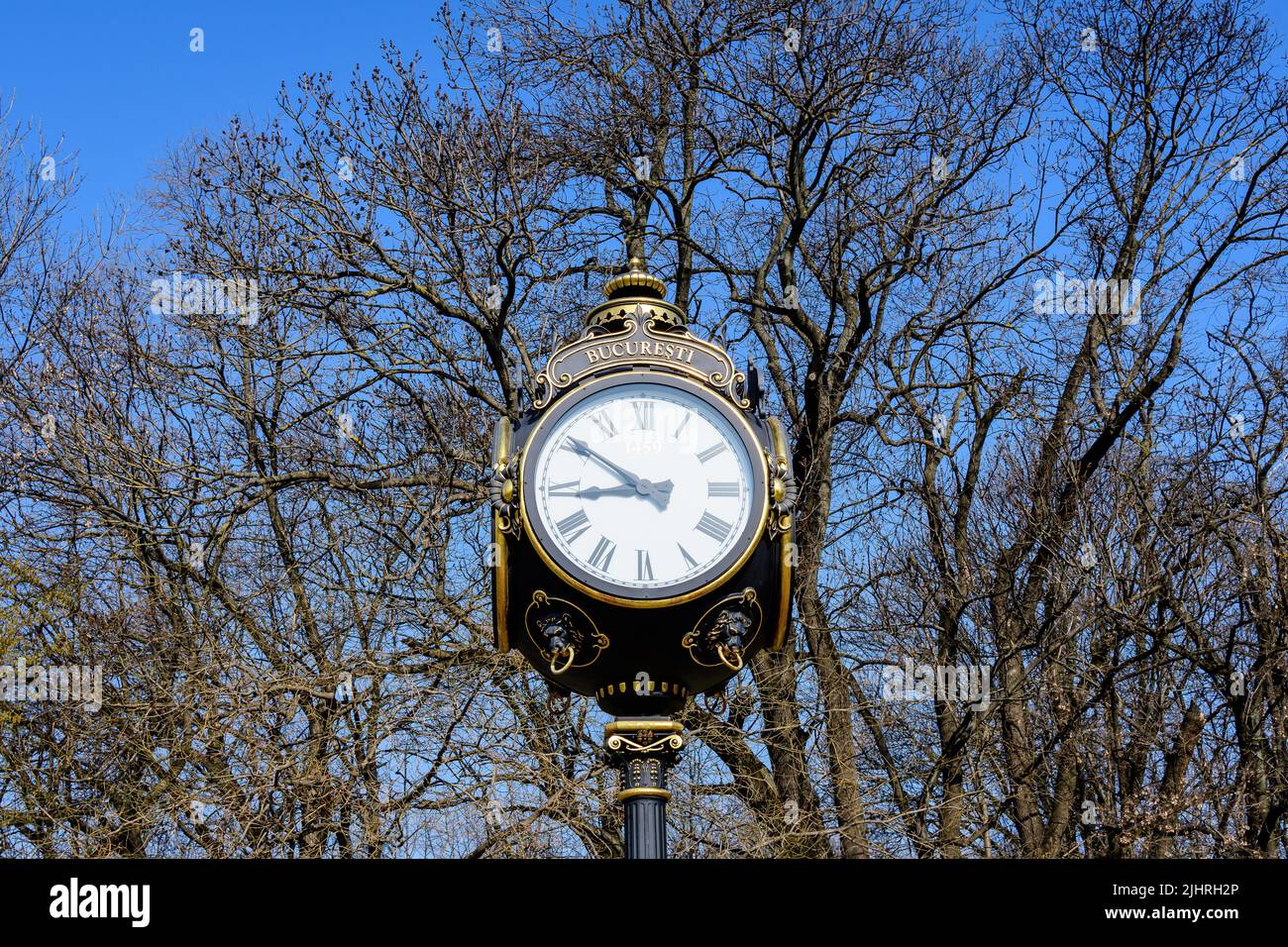 Vintage style black and grey metallic clock towards clear blue sky in ...
