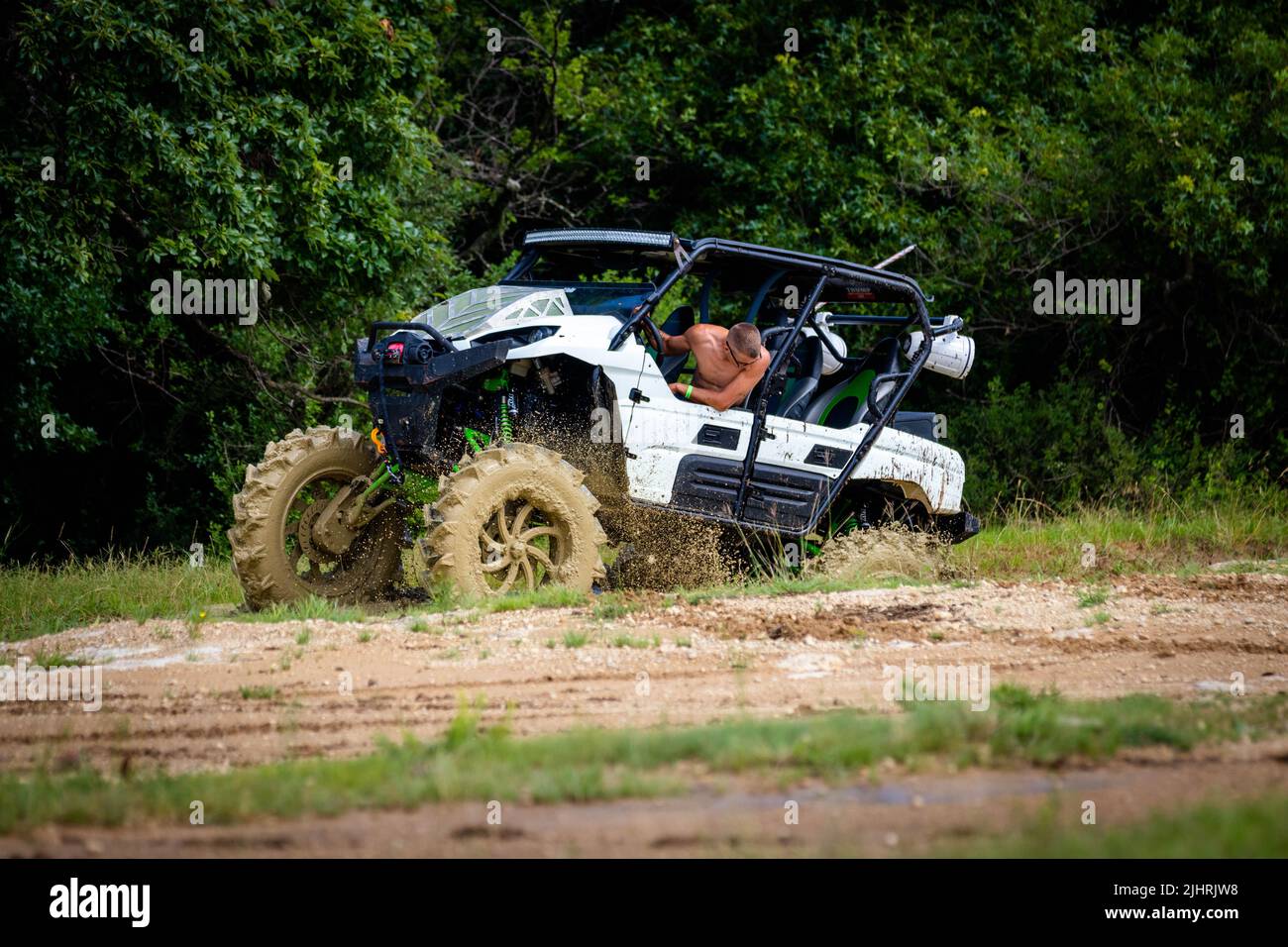 An ATV with people driving around and racing on a dirty muddy field at ...