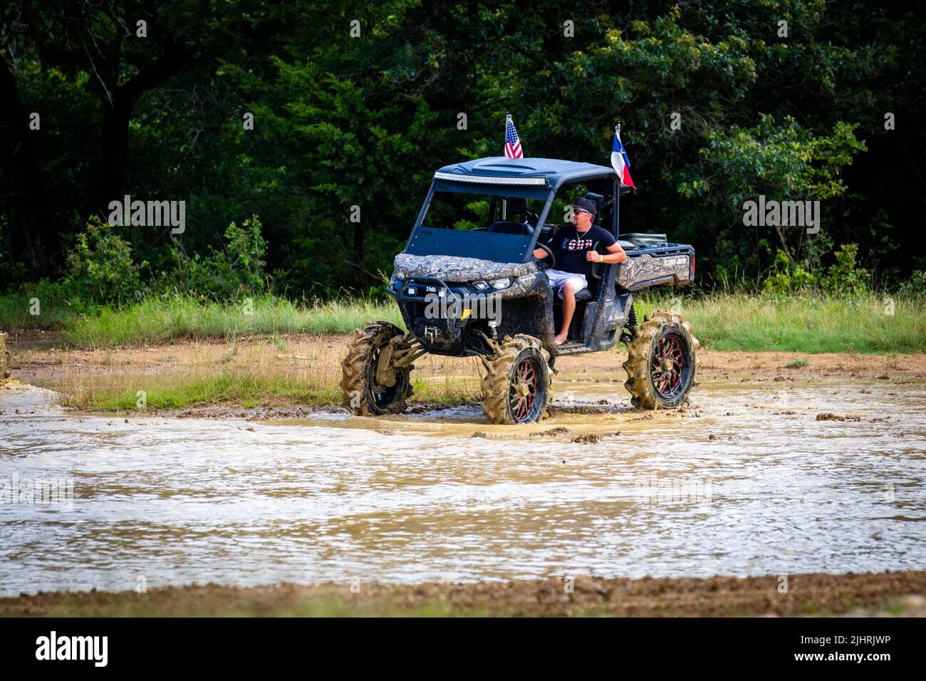 An ATV with people driving around and racing on a dirty muddy field at ...
