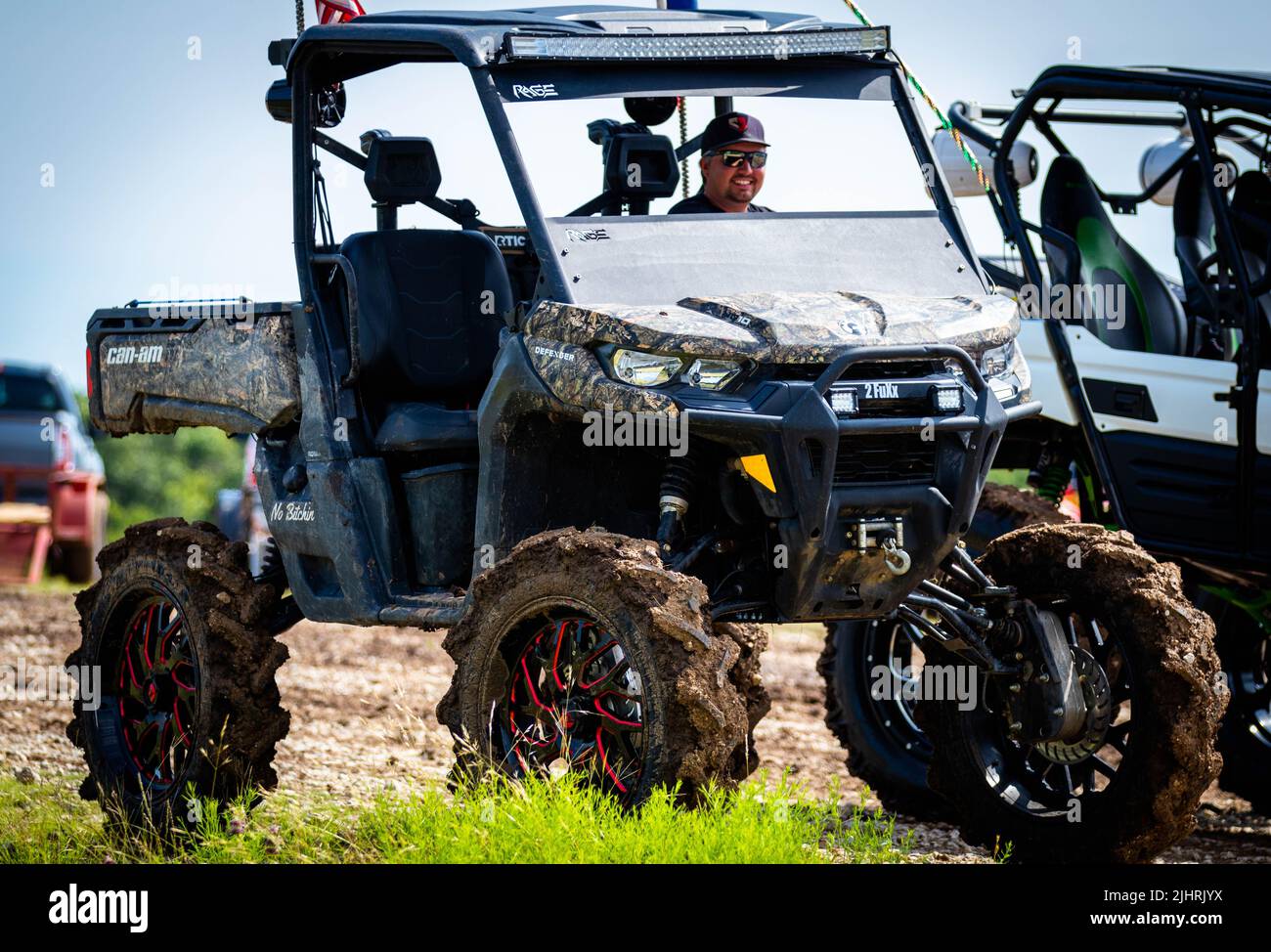 An ATV with people driving around and racing on a dirty muddy field at ...