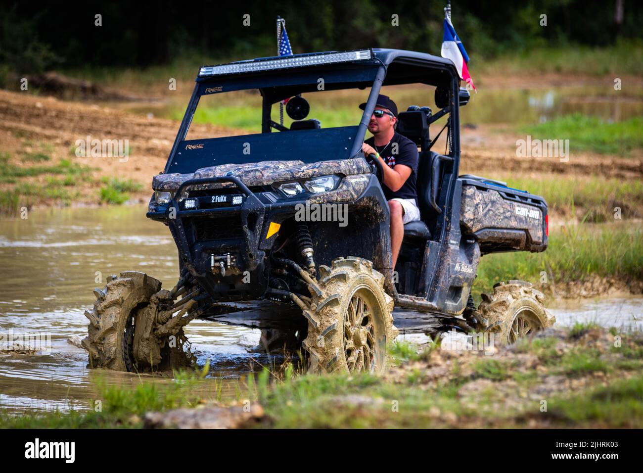 An ATV with people driving around and racing on a dirty muddy field at ...