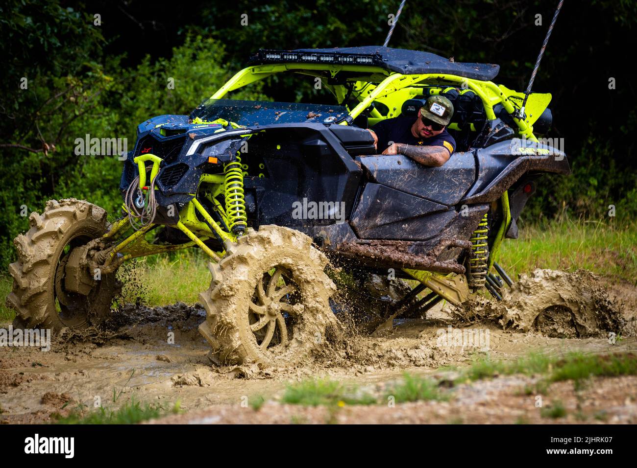An ATV with people driving around and racing on a dirty muddy field at ...