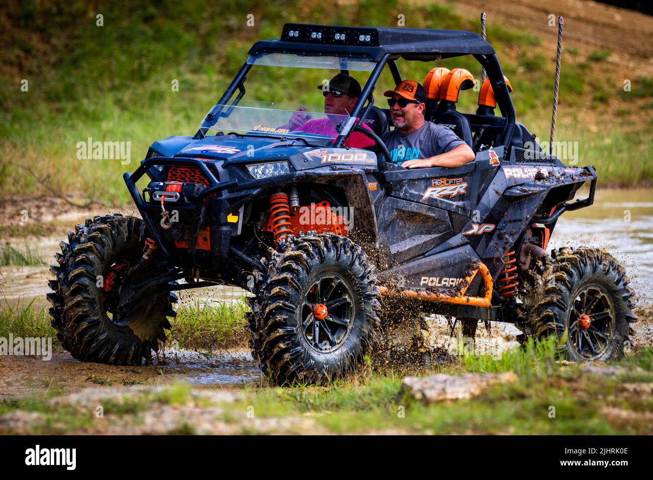 An ATV with people driving around and racing on a dirty muddy field at ...