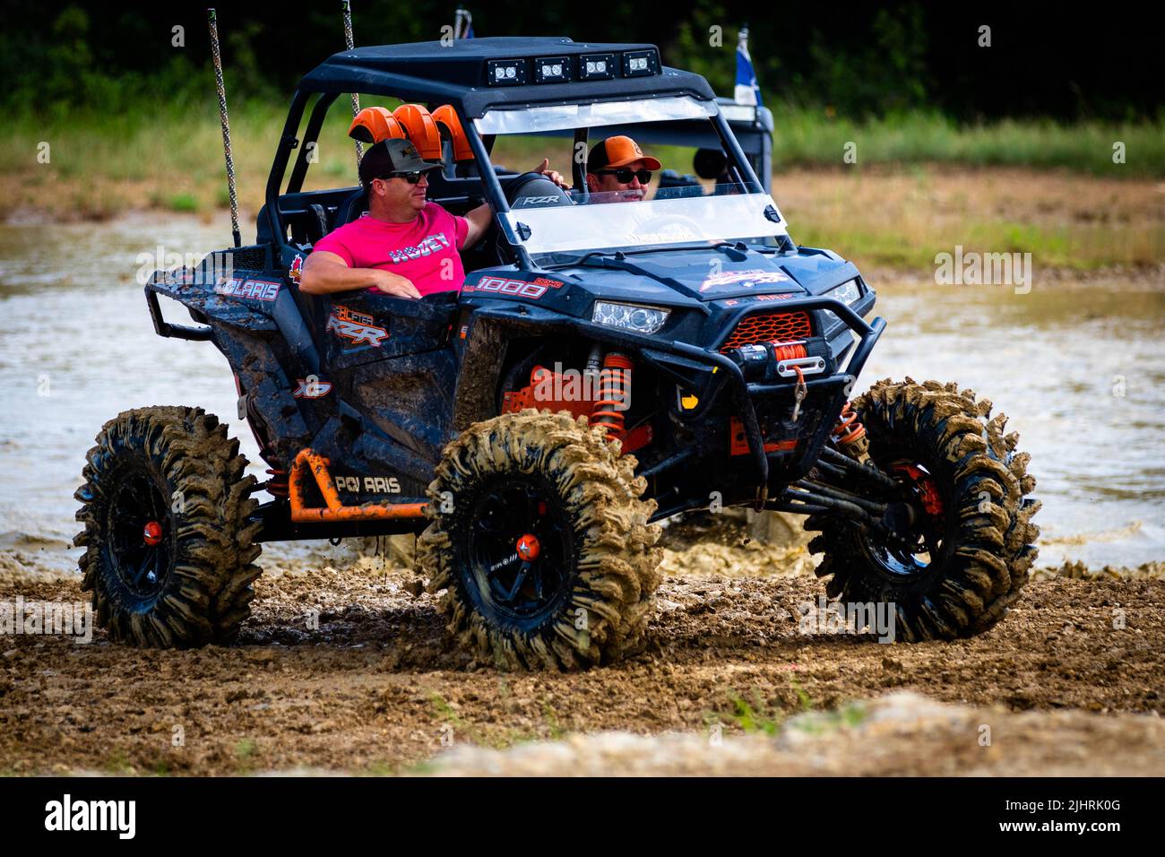 An ATV with people driving around and racing on a dirty muddy field at ...