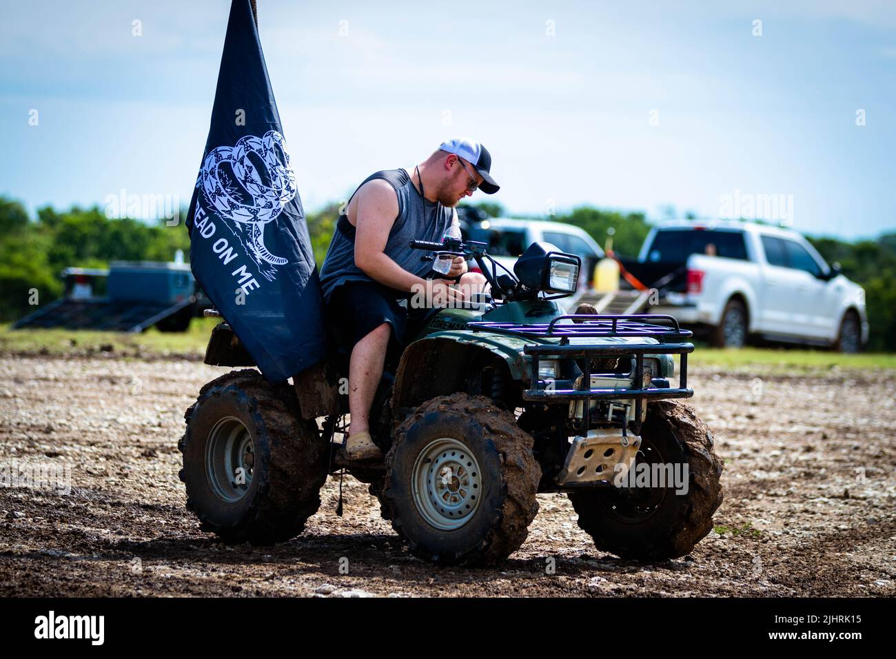 An ATV with a male driving around and racing on a dirty muddy field at ...
