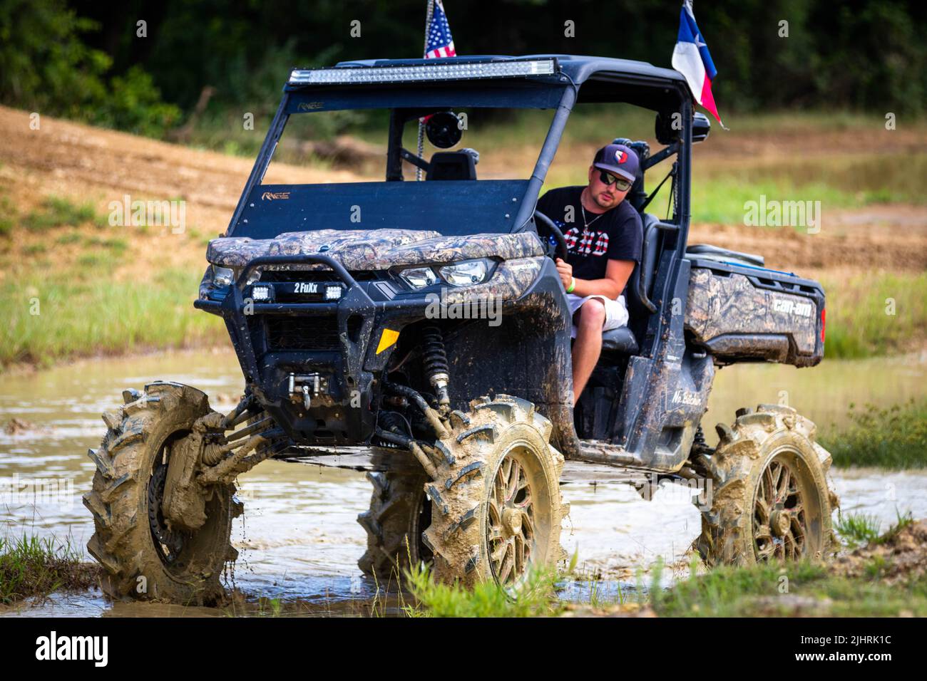 An ATV with people driving around and racing on a dirty muddy field at ...