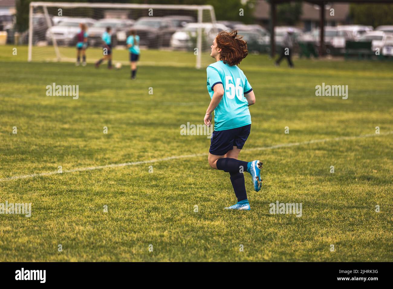 A young girl in blue uniform running while playing soccer at Youth ...