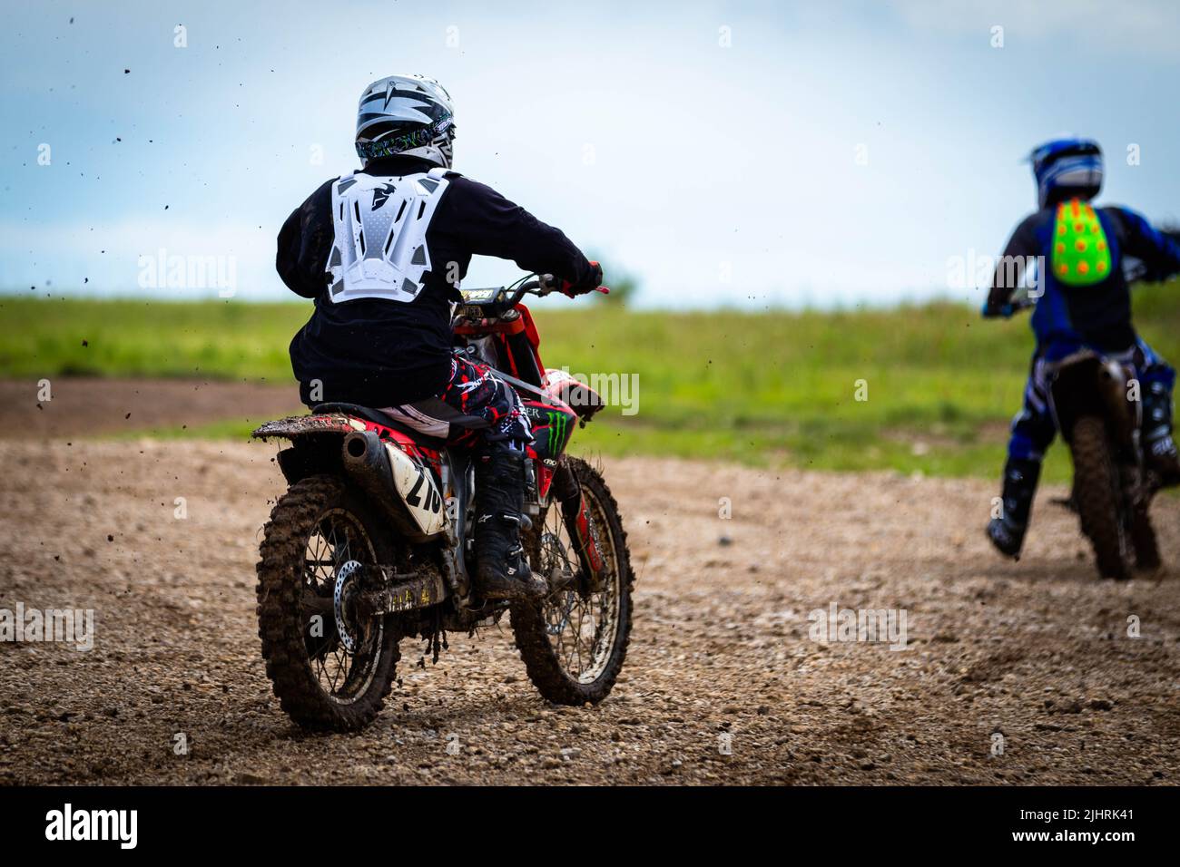 A professional in full gear driving a motorcycle on a muddy field at ...