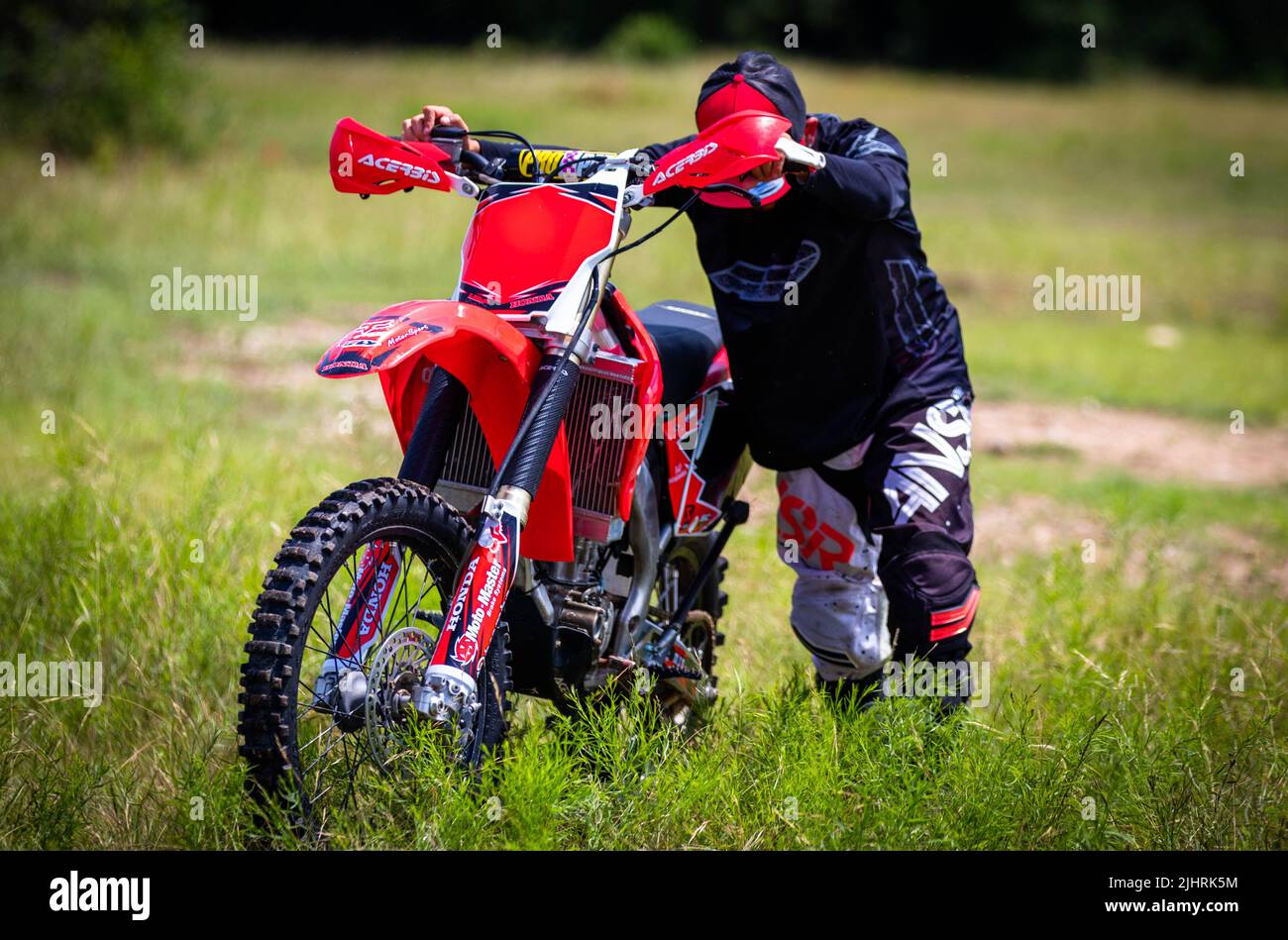 A person pushing their red motorcycle on a field at Rock Fest in 2020 ...